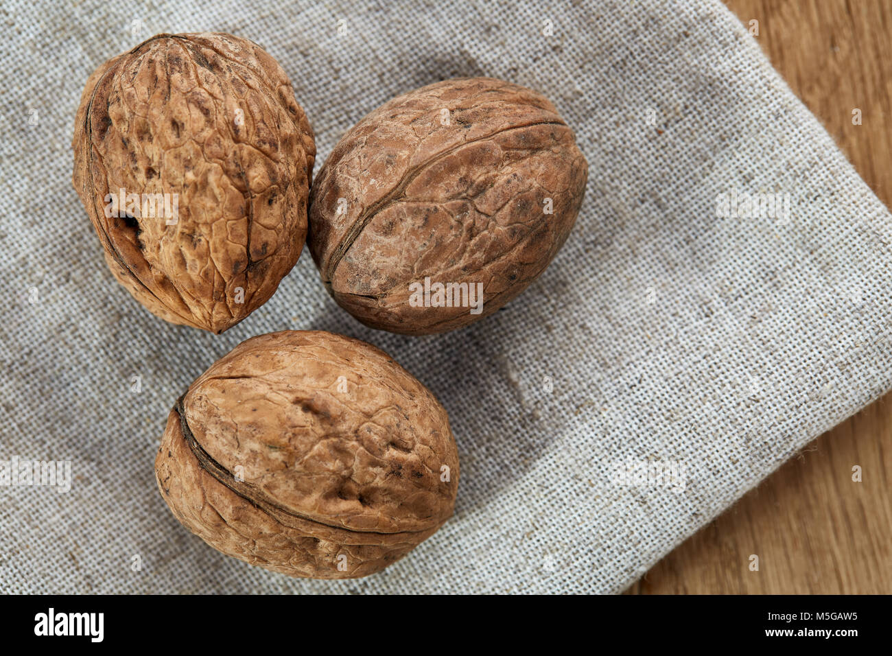 A stack of hard shells of walnuts piled together on light grey fabric ...