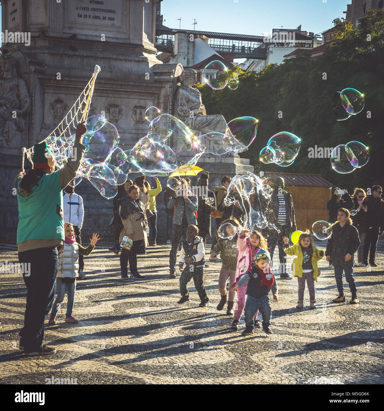 Children chasing bubbles in Rossio Square, Lisbon, Portugal Stock Photo ...