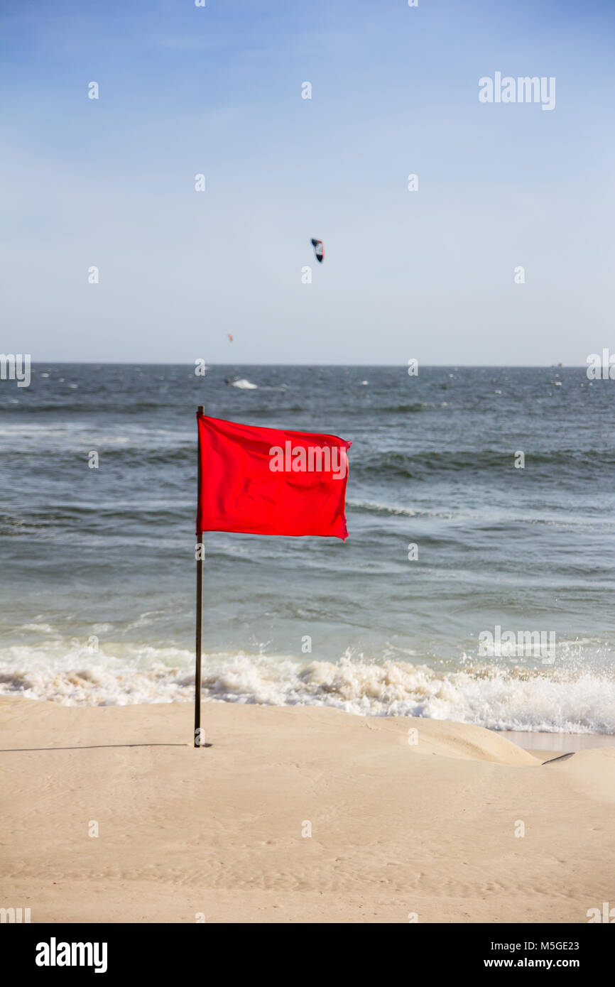 red flag at the beach, with kitesurfers in the background Stock Photo ...