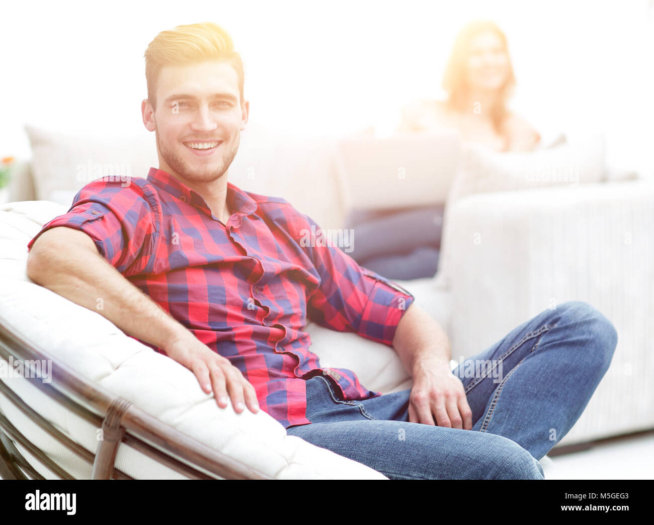 smiling young male sitting in a big chair Stock Photo - Alamy