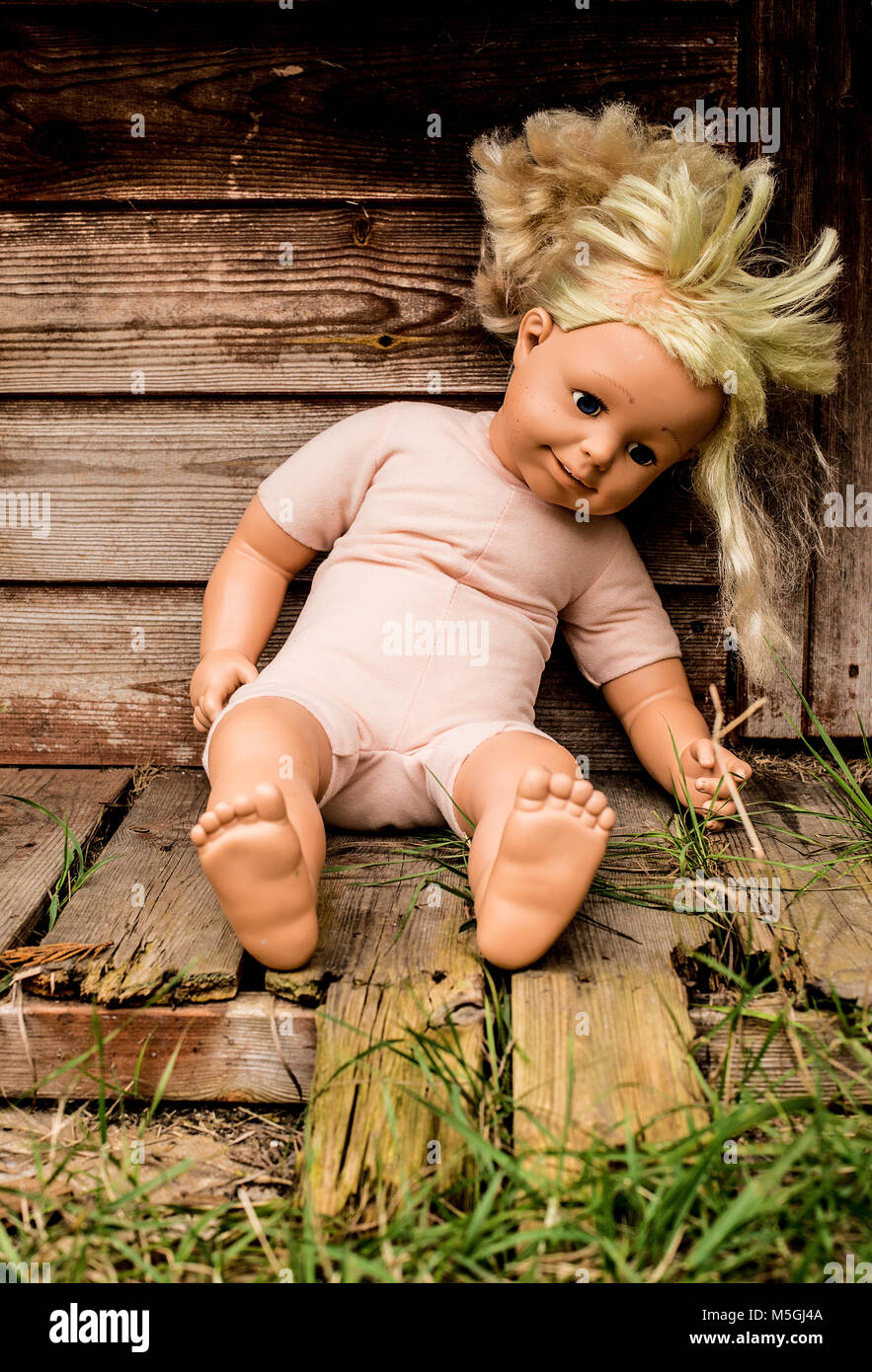 Old neglected doll sitting in front of derelict building Stock Photo ...