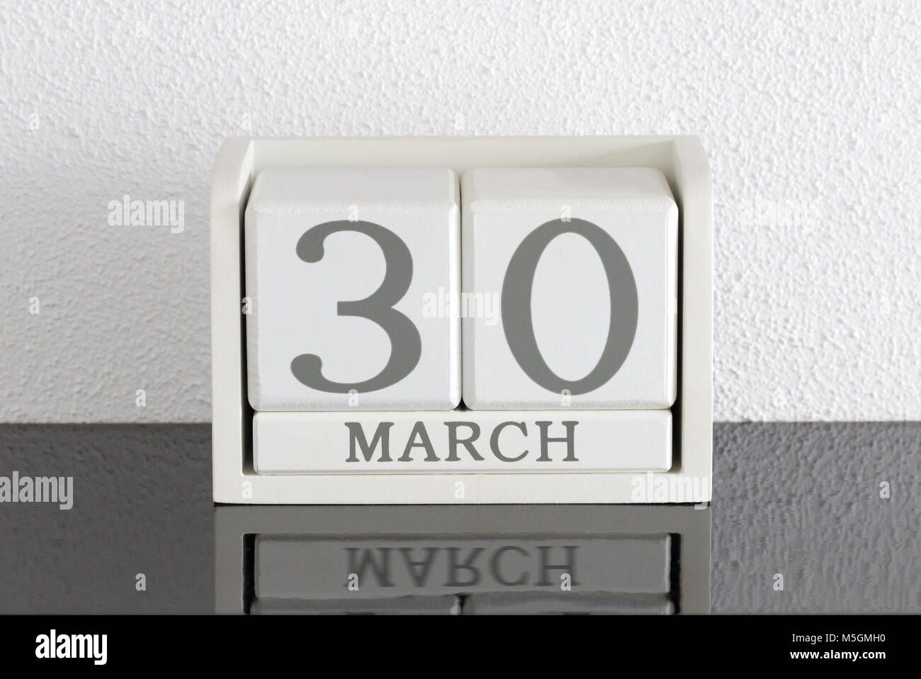 White block calendar present date 30 and month March on white wall ...