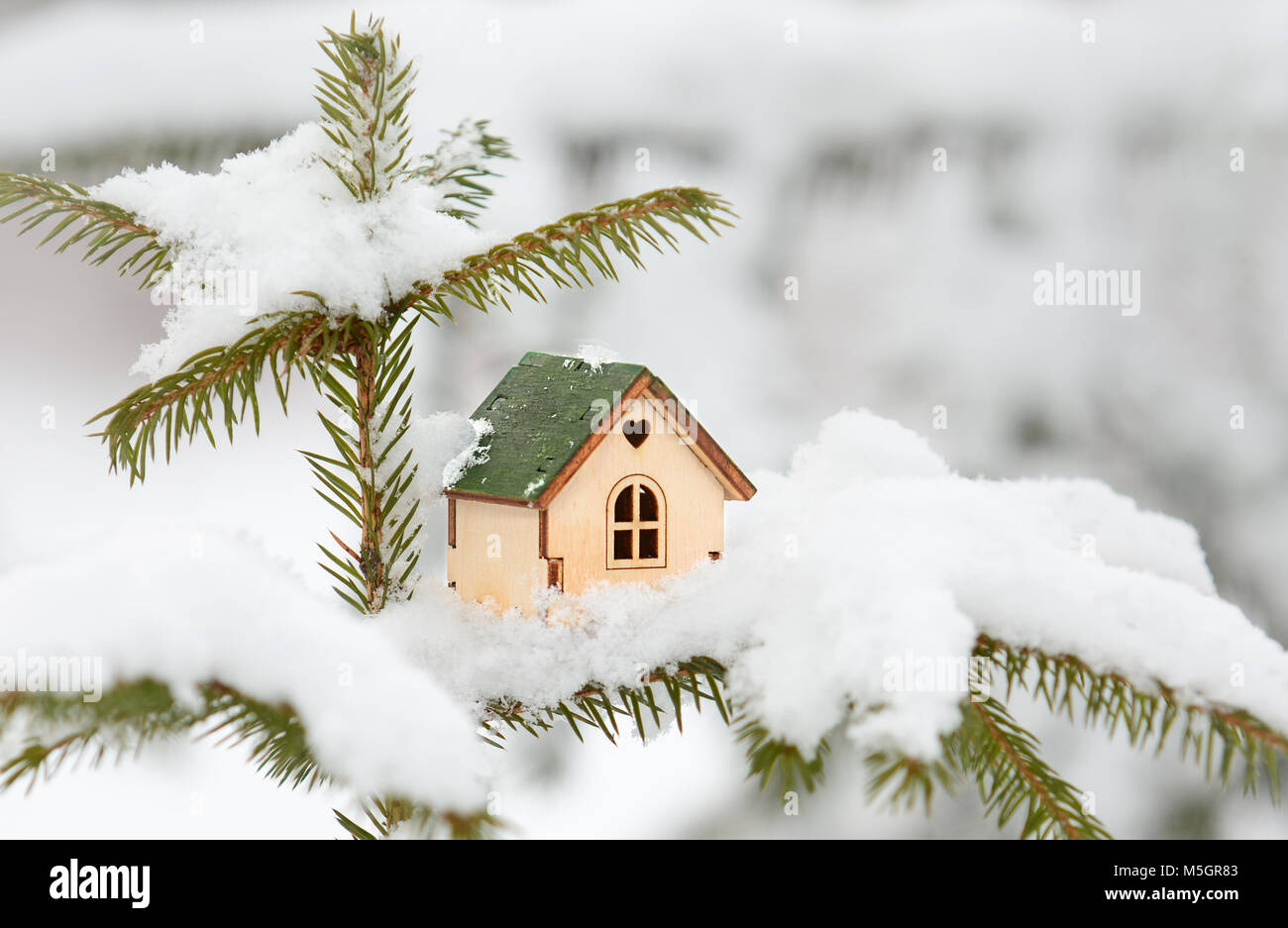 Wooden small cute toy house with green roof on сhristmas tree in snow ...