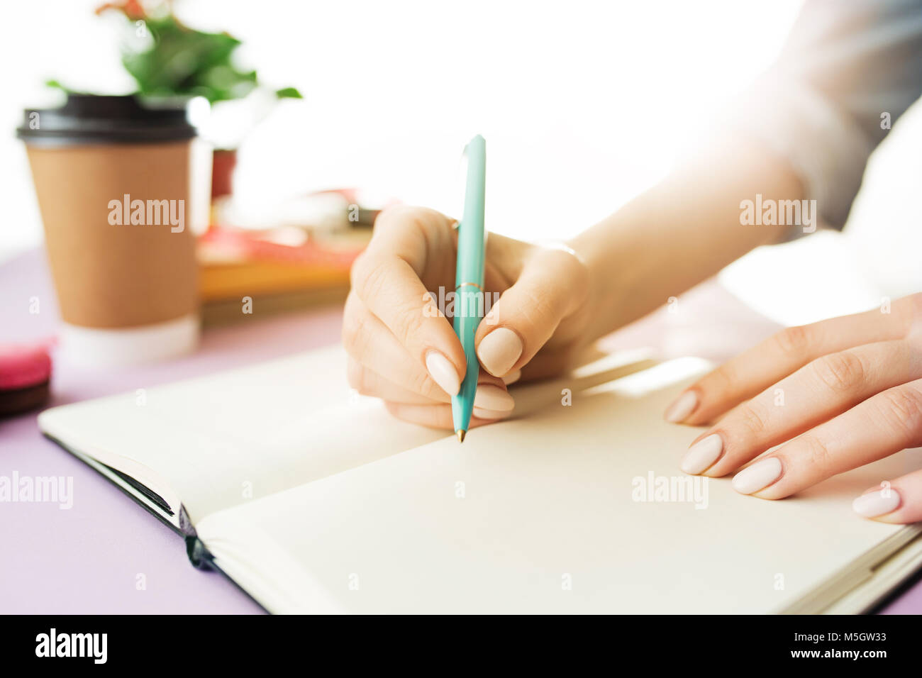 The female hands holding pen. The trendy pink desk Stock Photo - Alamy