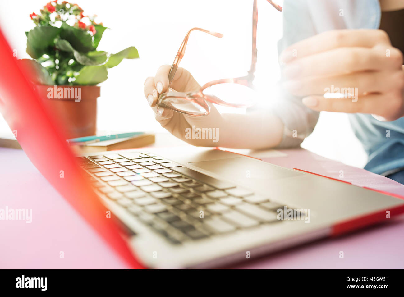 Woman working on computer in office and holding glasses Stock Photo - Alamy