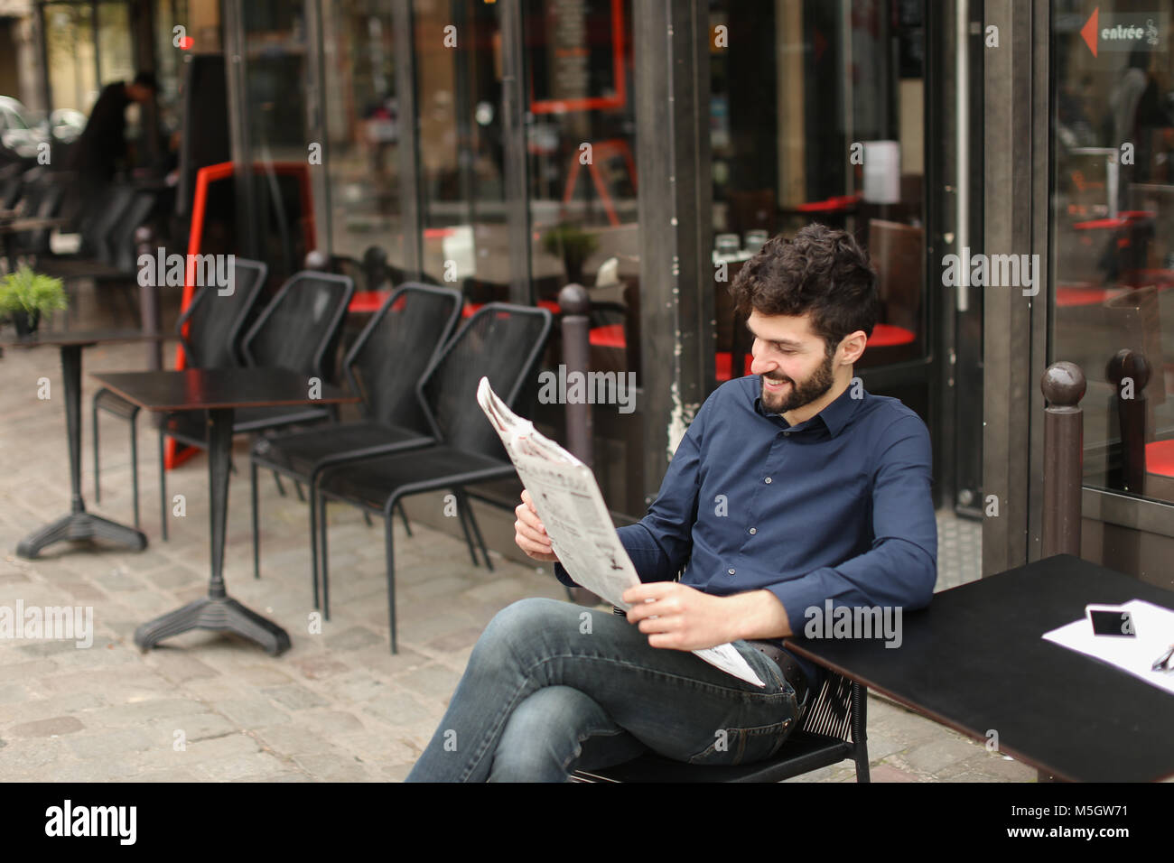 Journalist with close up face reading newspaper article at cafe Stock ...