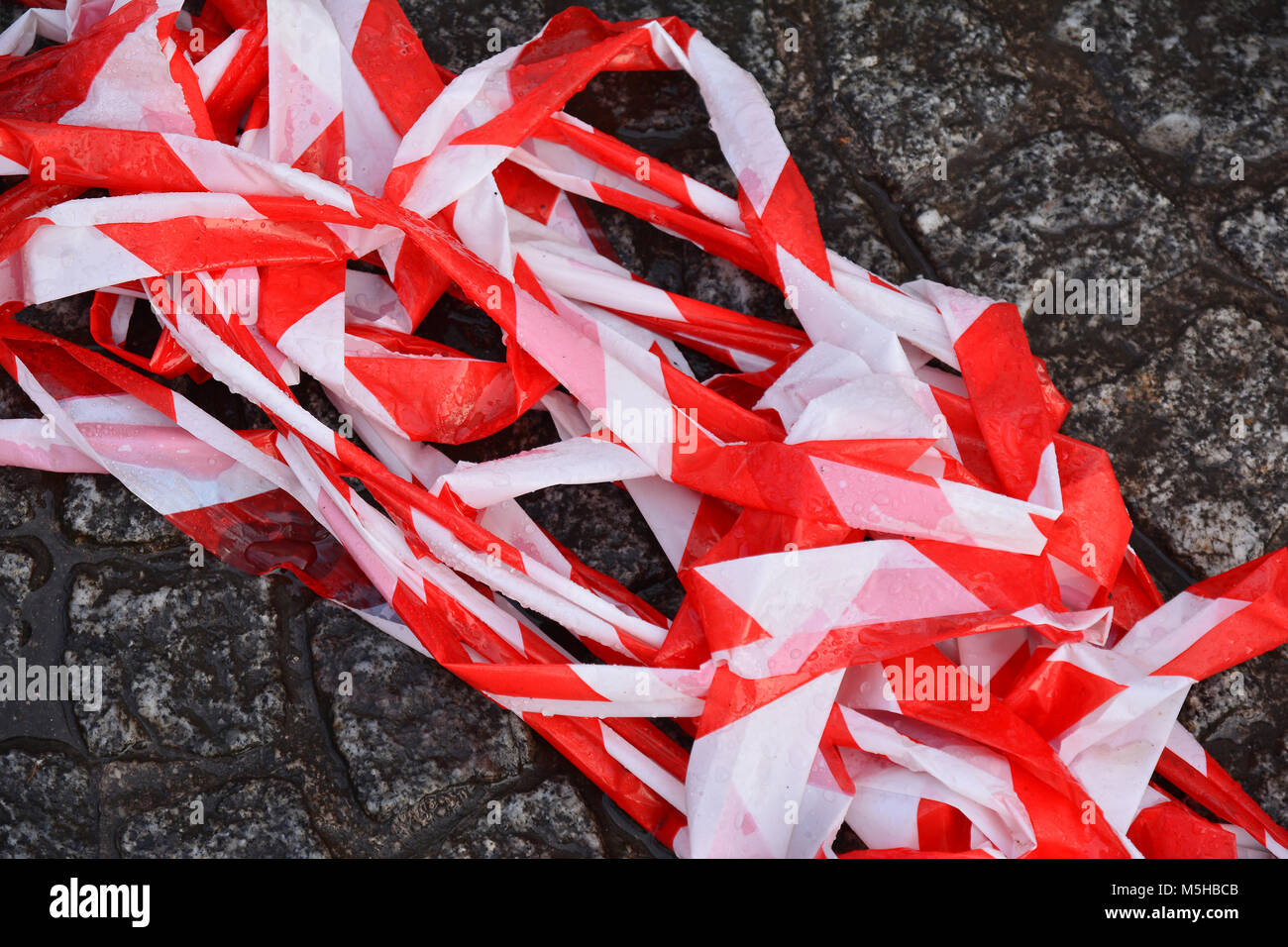 A discarded pile of red and white barrier tape lying on the ground ...