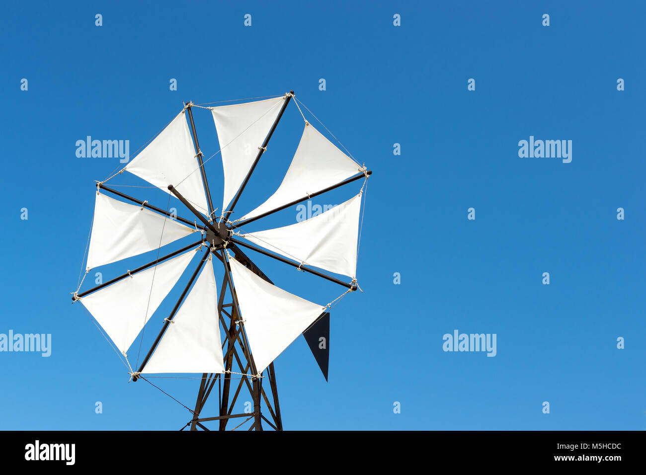 Decorative windmill with white propeller installed on thatched roof ...