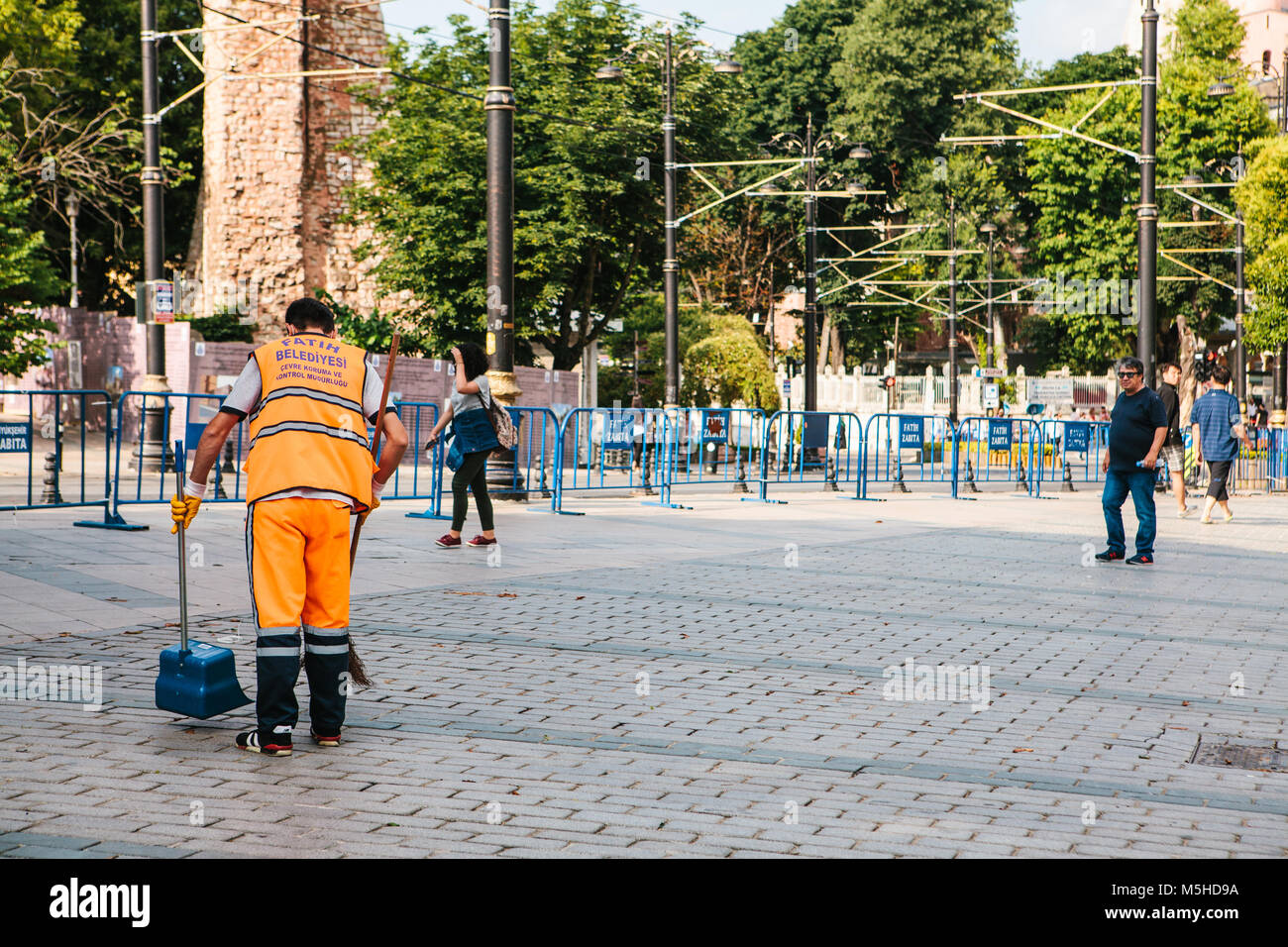Istanbul, June 15, 2017: Janitor in bright orange uniform sweeping the ...