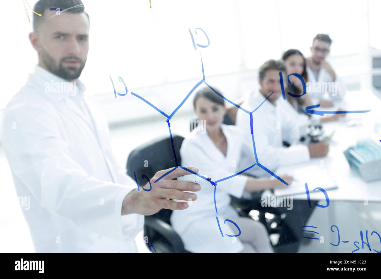 from behind the glass. a scientist standing near the blackboard in the ...