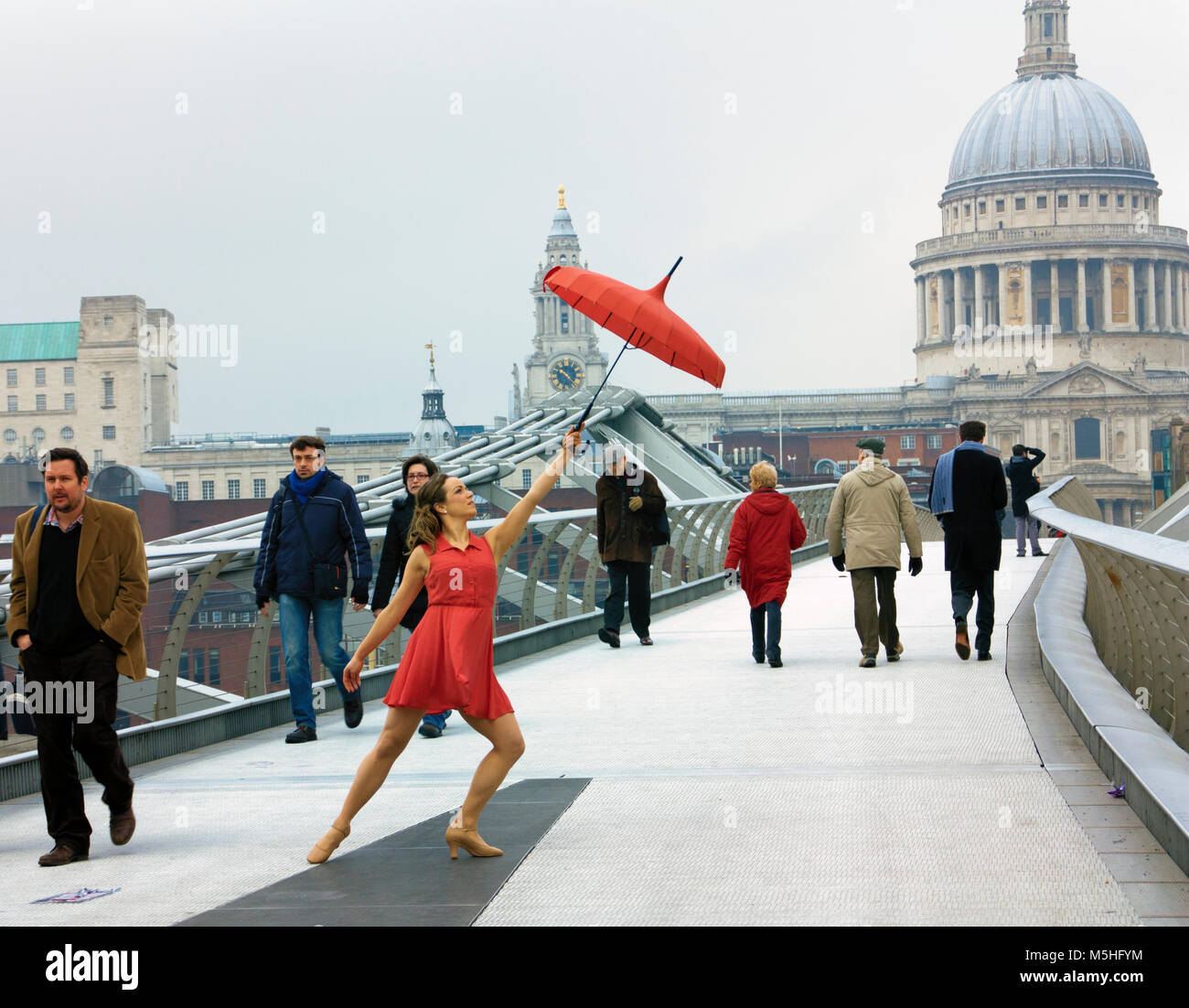 Model in red dress with umbrella posing on the Millennium Bridge with ...