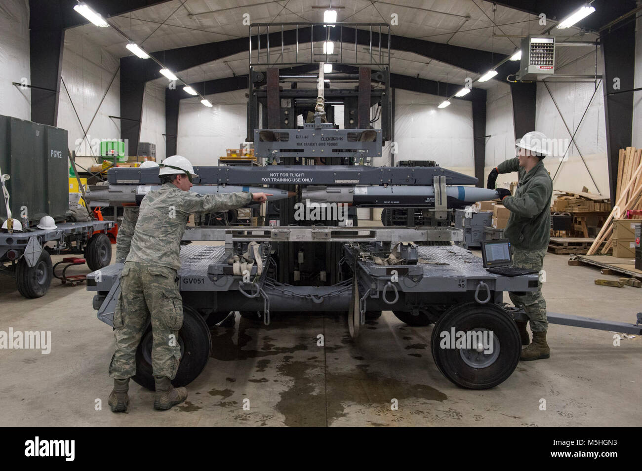 Airmen with the 3rd Munitions Squadron transport a rack of inert small ...