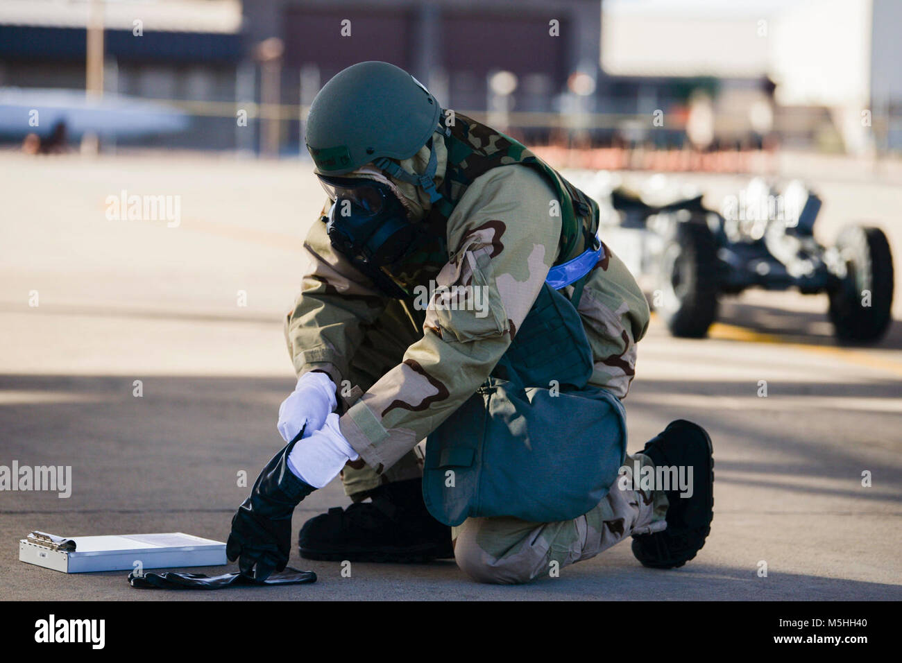 A U.S. Airman dons full mission-oriented protective posture gear during ...