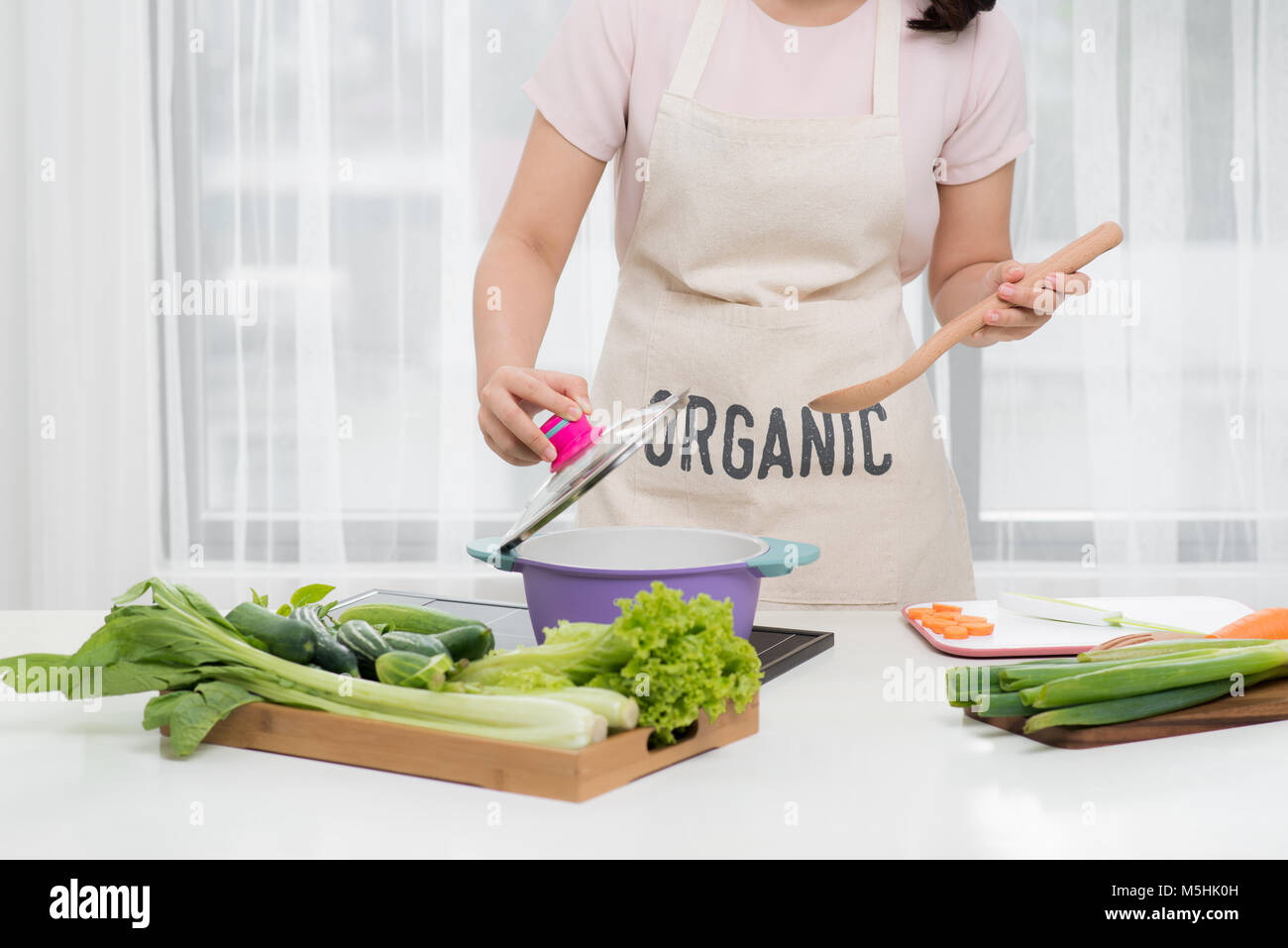 Healthy food. Asian woman cooking in the kitchen with wooden spoon ...