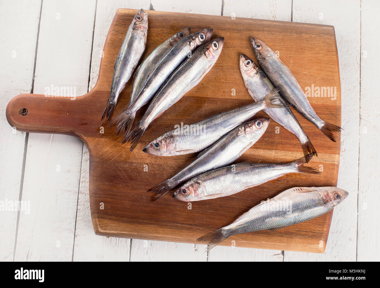 Fresh sprat fish on a white wooden background. Top view Stock Photo - Alamy