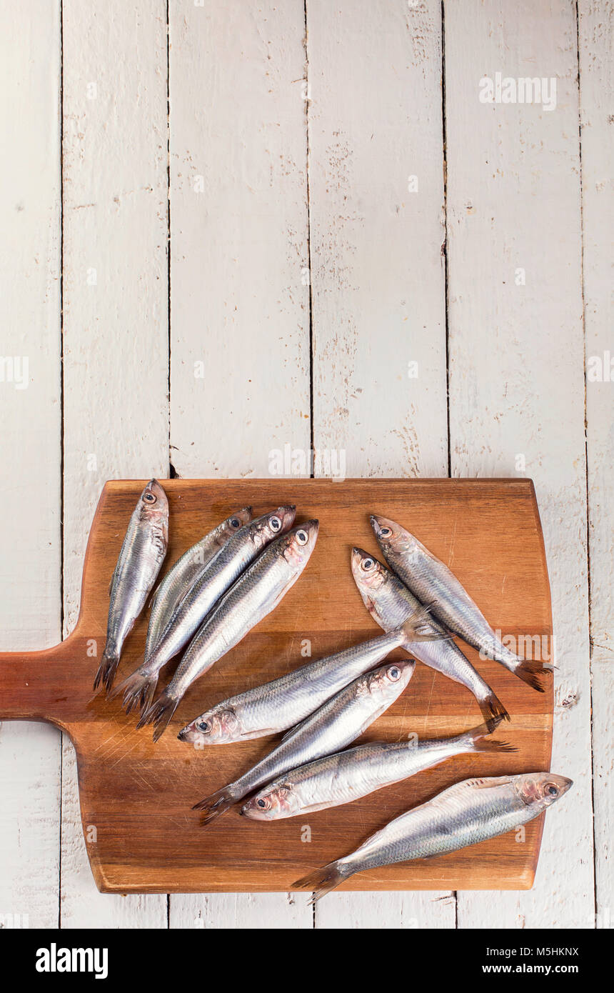 Fresh sprat fish on a white wooden background. Top view Stock Photo - Alamy