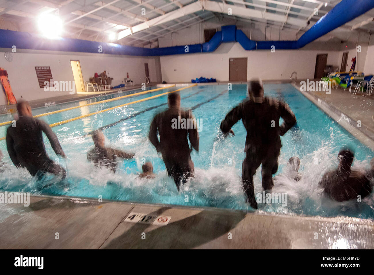 Airmen jump into a pool during a water survival assessment, Feb. 9 ...