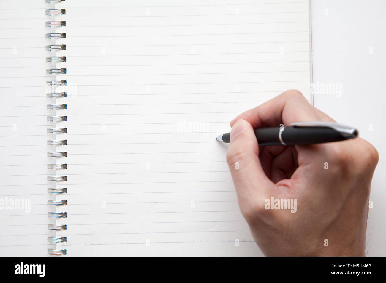 hand holding a pen on white notebook,overlooking Stock Photo - Alamy