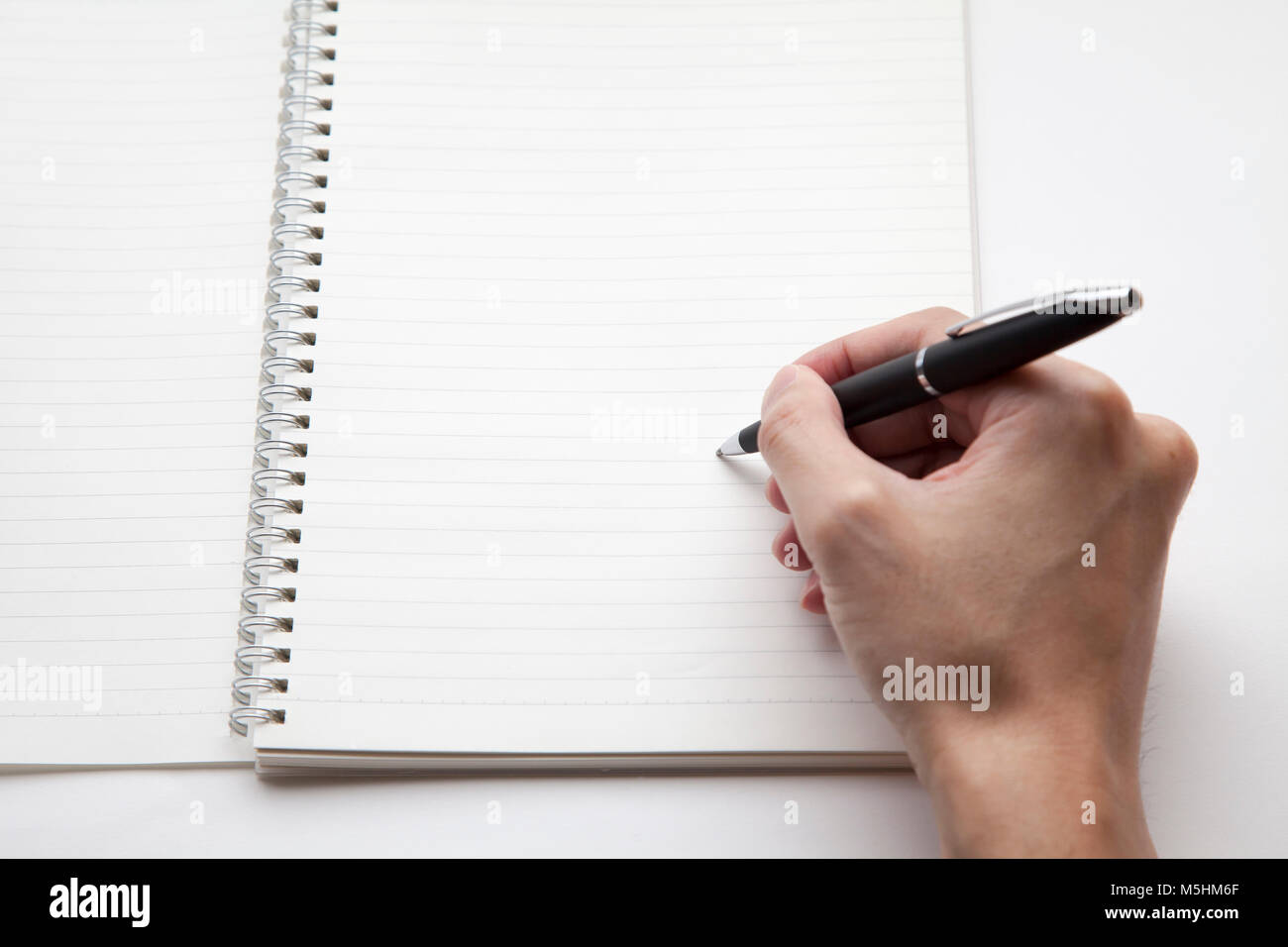 hand holding a pen on white notebook,overlooking Stock Photo - Alamy