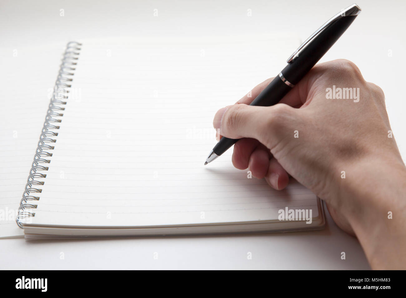hand holding a pen on white notebook,overlooking Stock Photo - Alamy