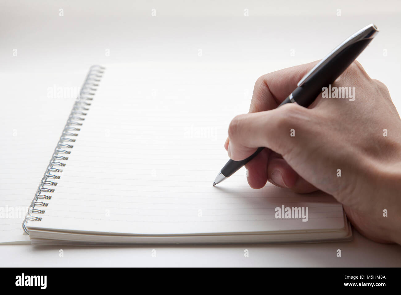 hand holding a pen on white notebook,overlooking Stock Photo - Alamy