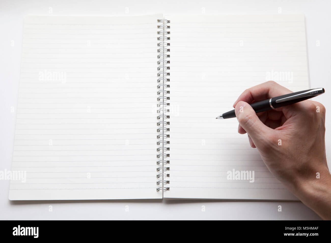 hand holding a pen on white notebook,overlooking Stock Photo - Alamy