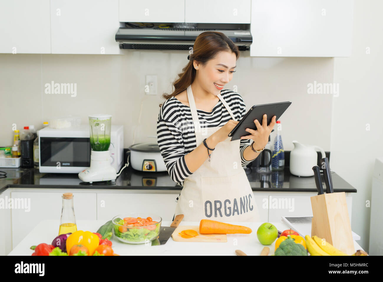 Young asian woman using a tablet computer to cook in her kitchen Stock ...