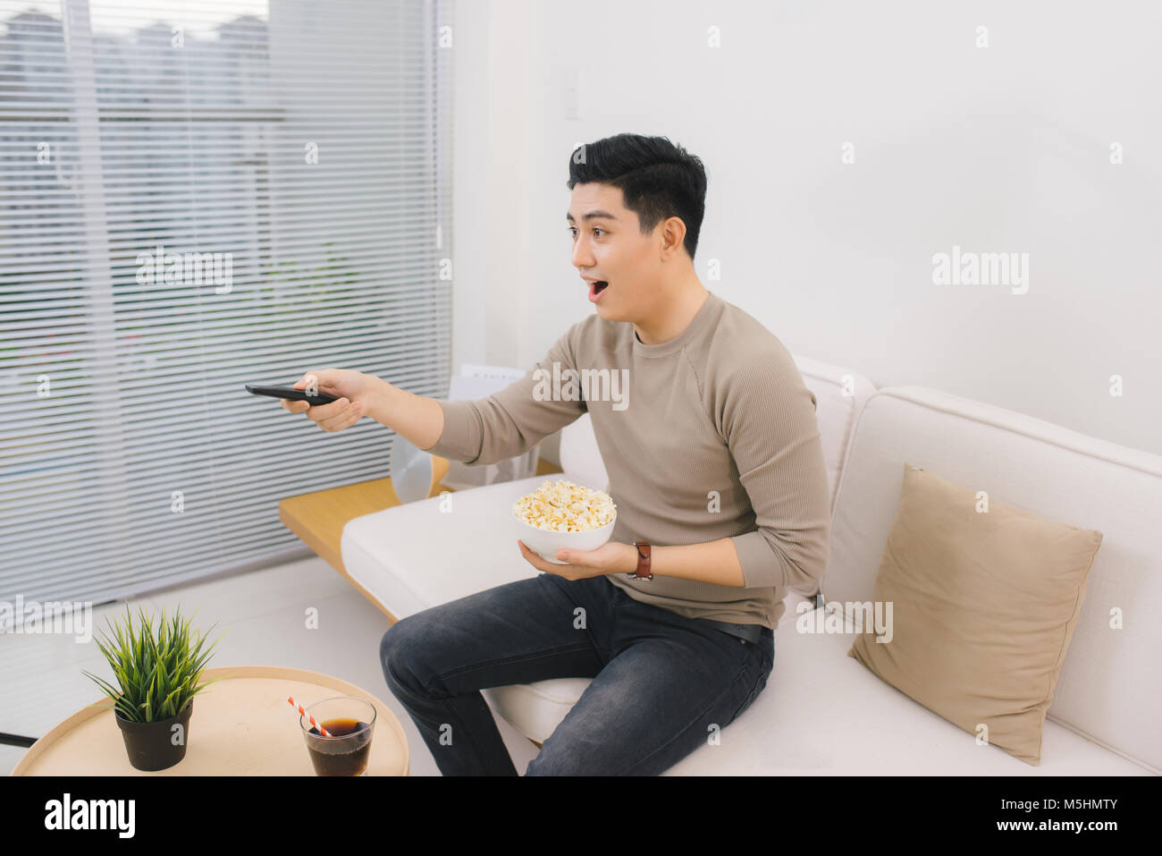 Young handsome man watching TV on the couch at home Stock Photo - Alamy