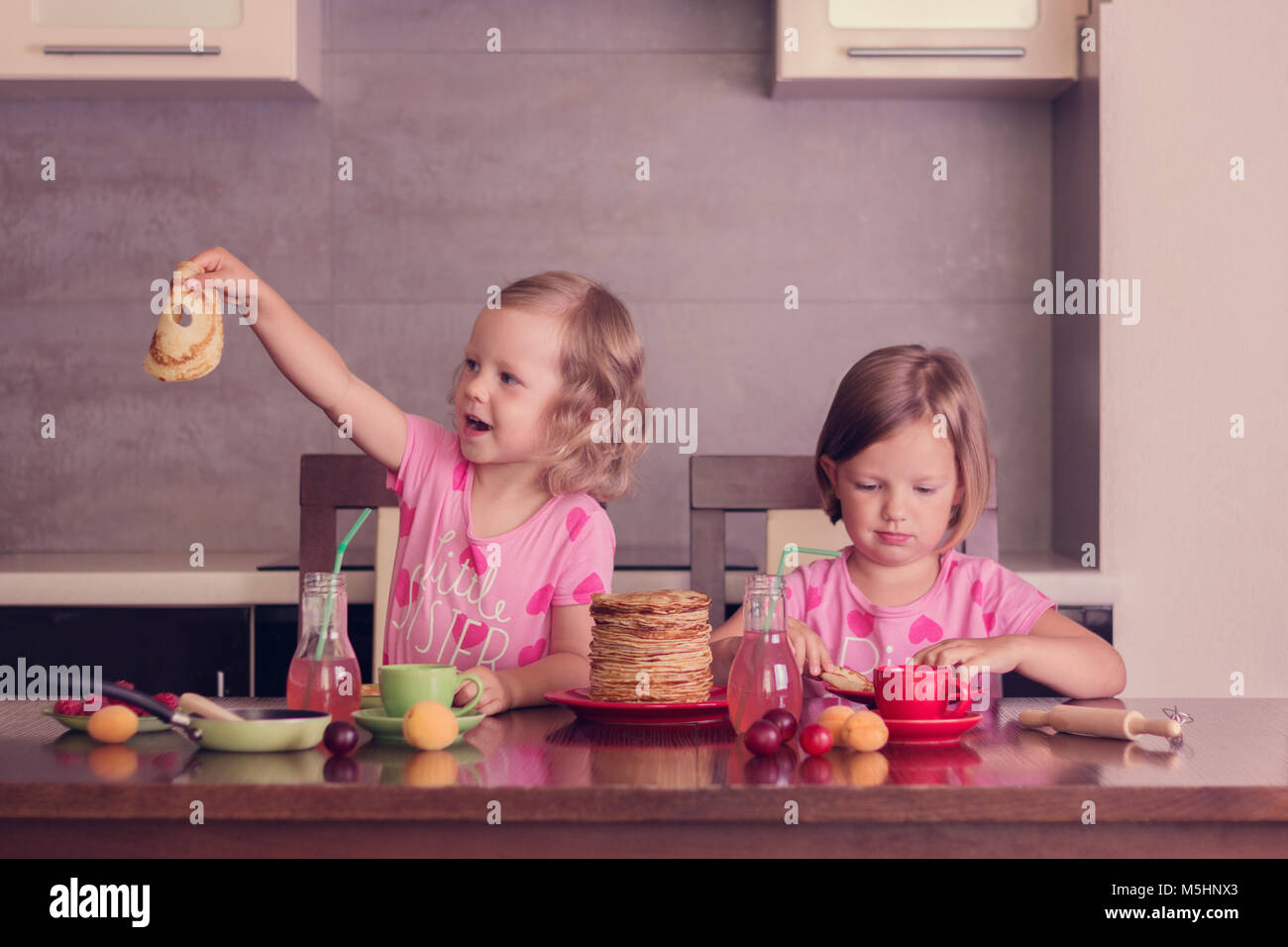 Pancake week. Little girls (sisters) eat pancakes. Selective focus ...