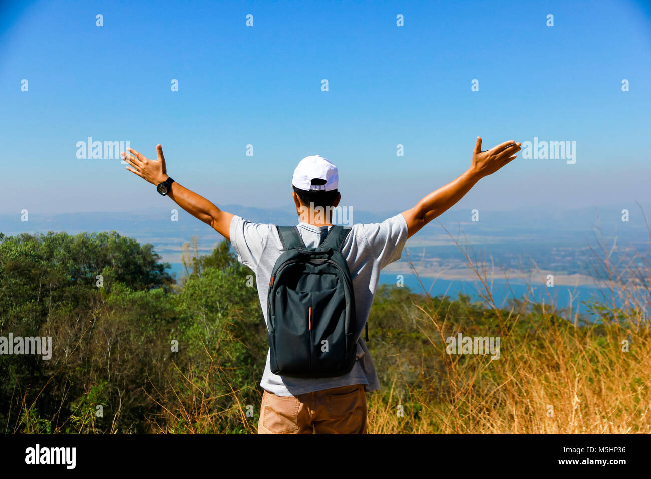 Adventurous man is standing on top of the mountain and enjoying the ...