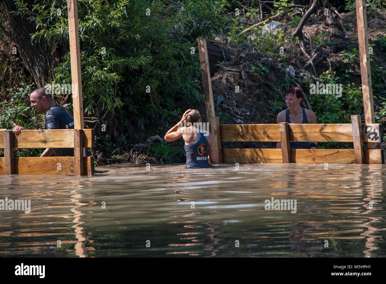 Two girls and a man are crossing a river challenge at the physical ...