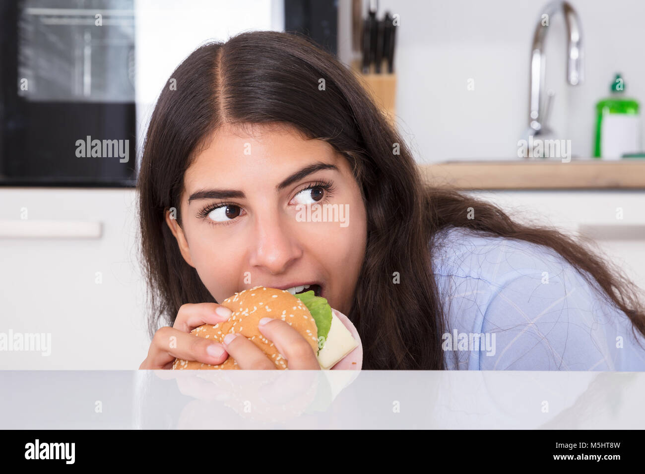 Close-up Of A Young Woman Secretly Eating Burger At Home Stock Photo ...