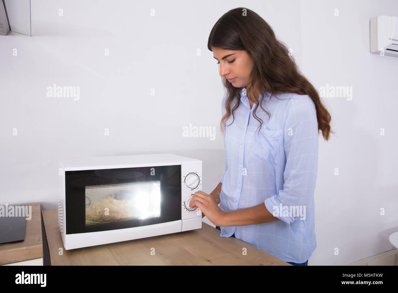 Young Woman Preparing Food In Microwave Oven On Kitchen Counter Stock ...