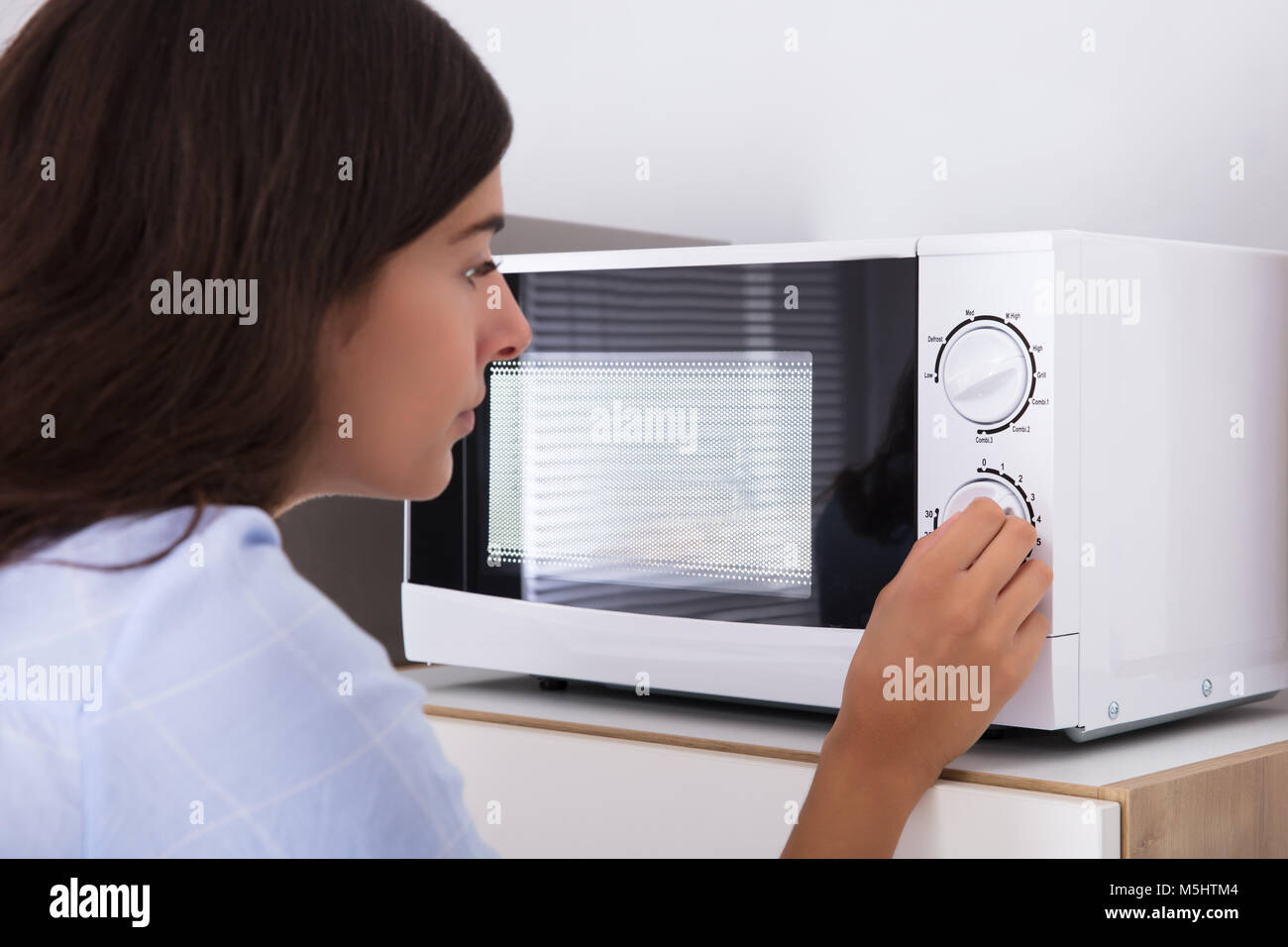 Young Woman Preparing Food In Microwave Oven On Kitchen Counter Stock ...