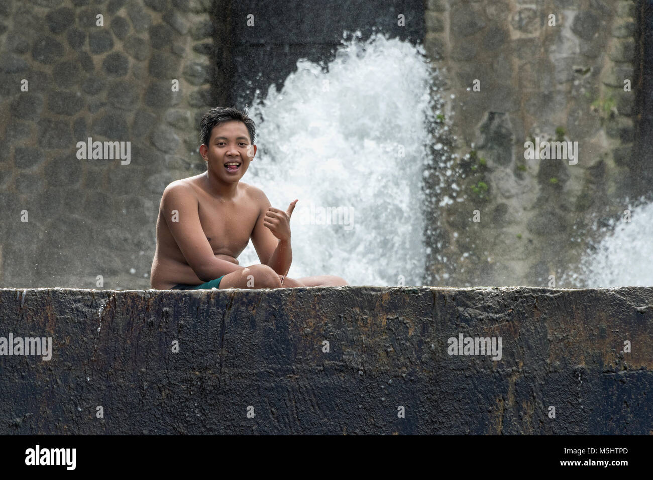 Thumbs up, boy sitting on the Tukad Unda Dam on a hot sunny day, Klongklong, Bali Stock Photo ...
