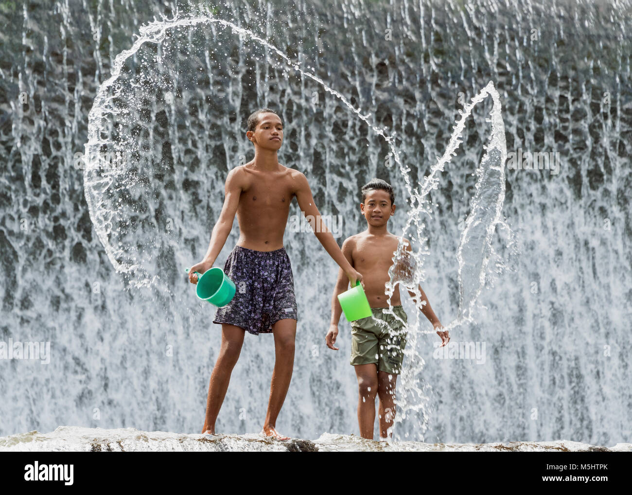 Teaching young brother to make water shapes, Tukad Unda Dam, Klongklong, Bali Stock Photo - Alamy