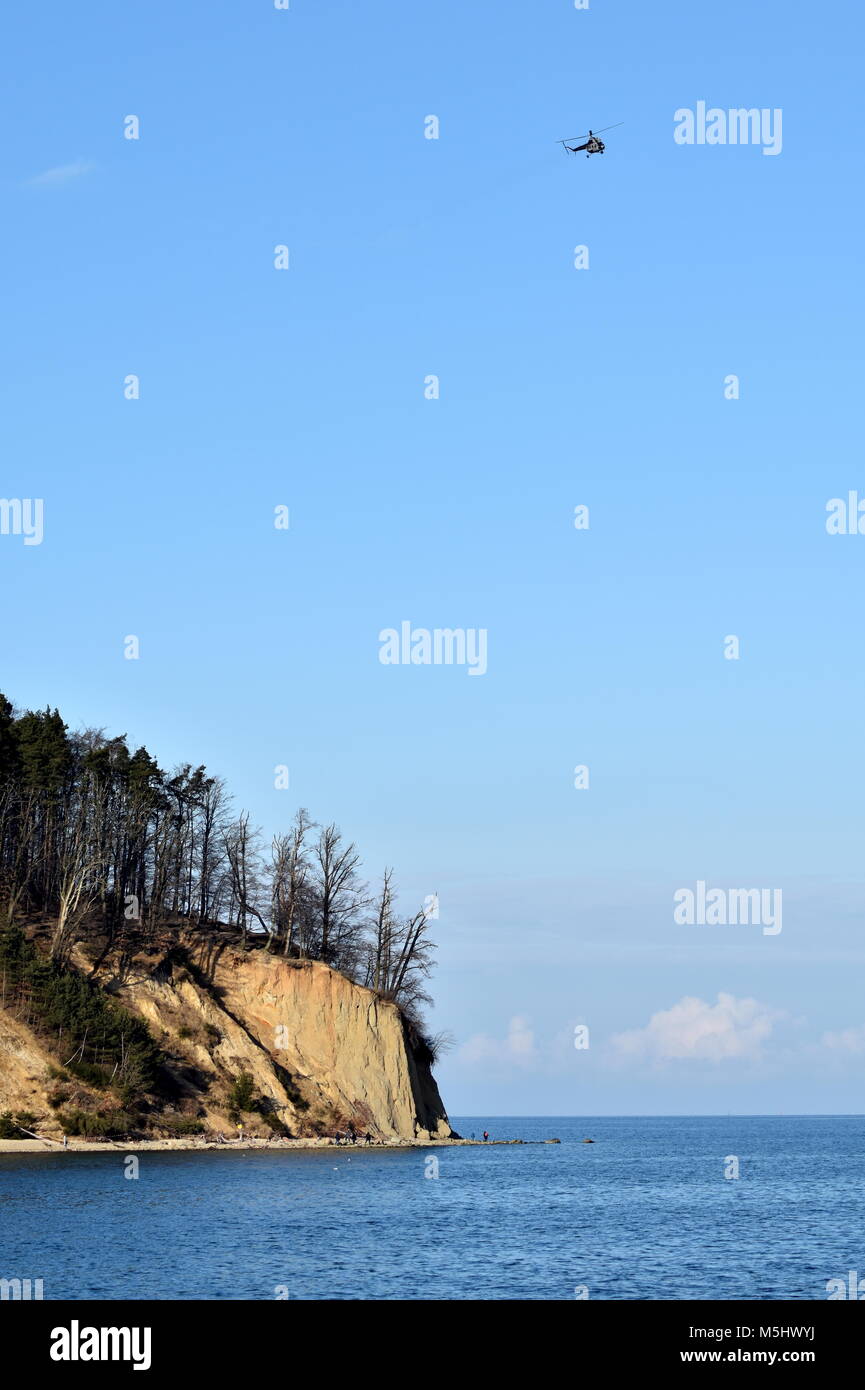 Photo of coastal scenery with helicopter flying high over the sea Stock ...