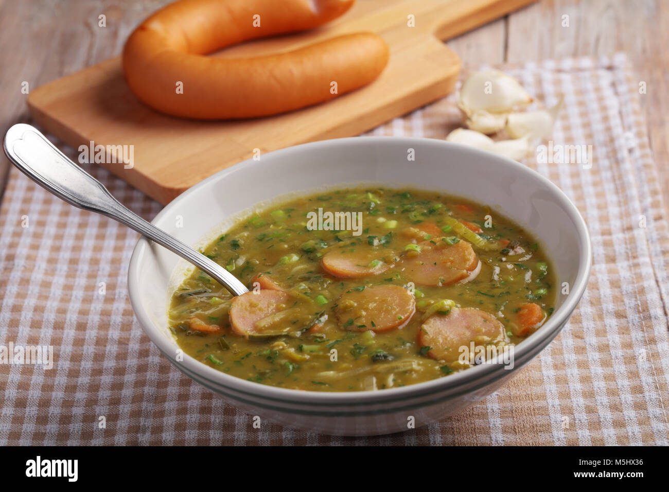 Dutch pea soup snert with smoked sausage Rookworst on a rustic table ...