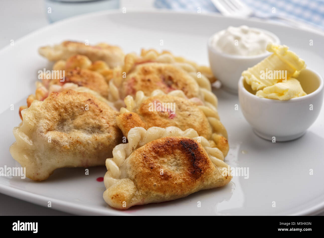 Traditional Polish dumplings Pierogi ruskie with sour cream and butter ...