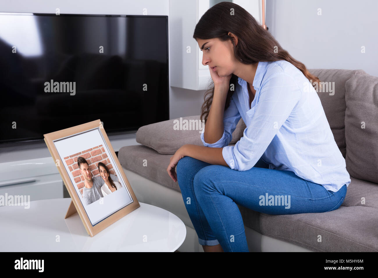 Sad Woman Holding Picture Frame Of Couple In Love At Home Stock Photo ...