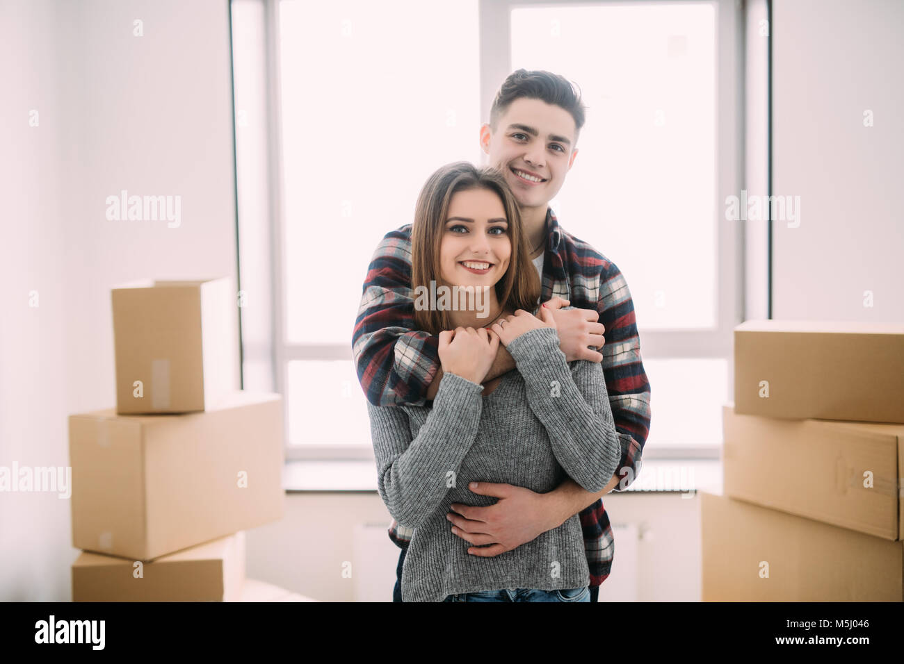 Beautiful couple is hugging, looking at camera and smiling while ...