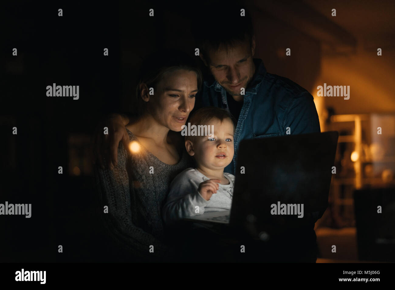 Family using laptop in the dark Stock Photo - Alamy