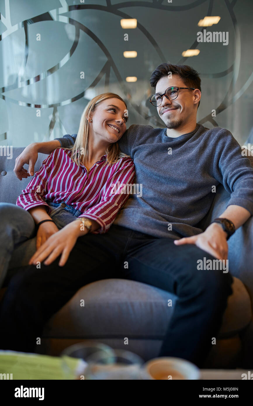 Happy relaxed couple sitting on sofa in a cafe Stock Photo - Alamy