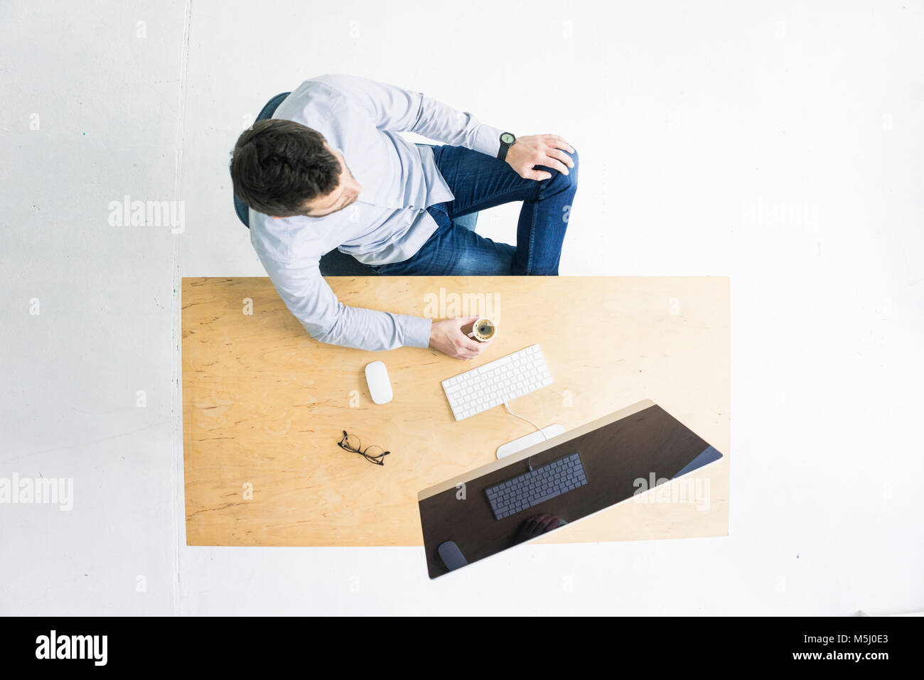 Businessman sitting at desk in office seen from above Stock Photo - Alamy