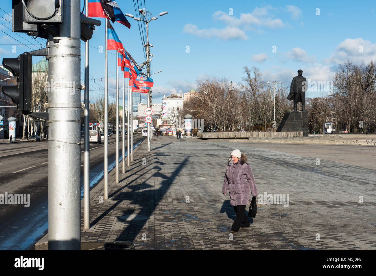 A woman walks on a central Lenin Square in Donetsk, DPR flags can be ...