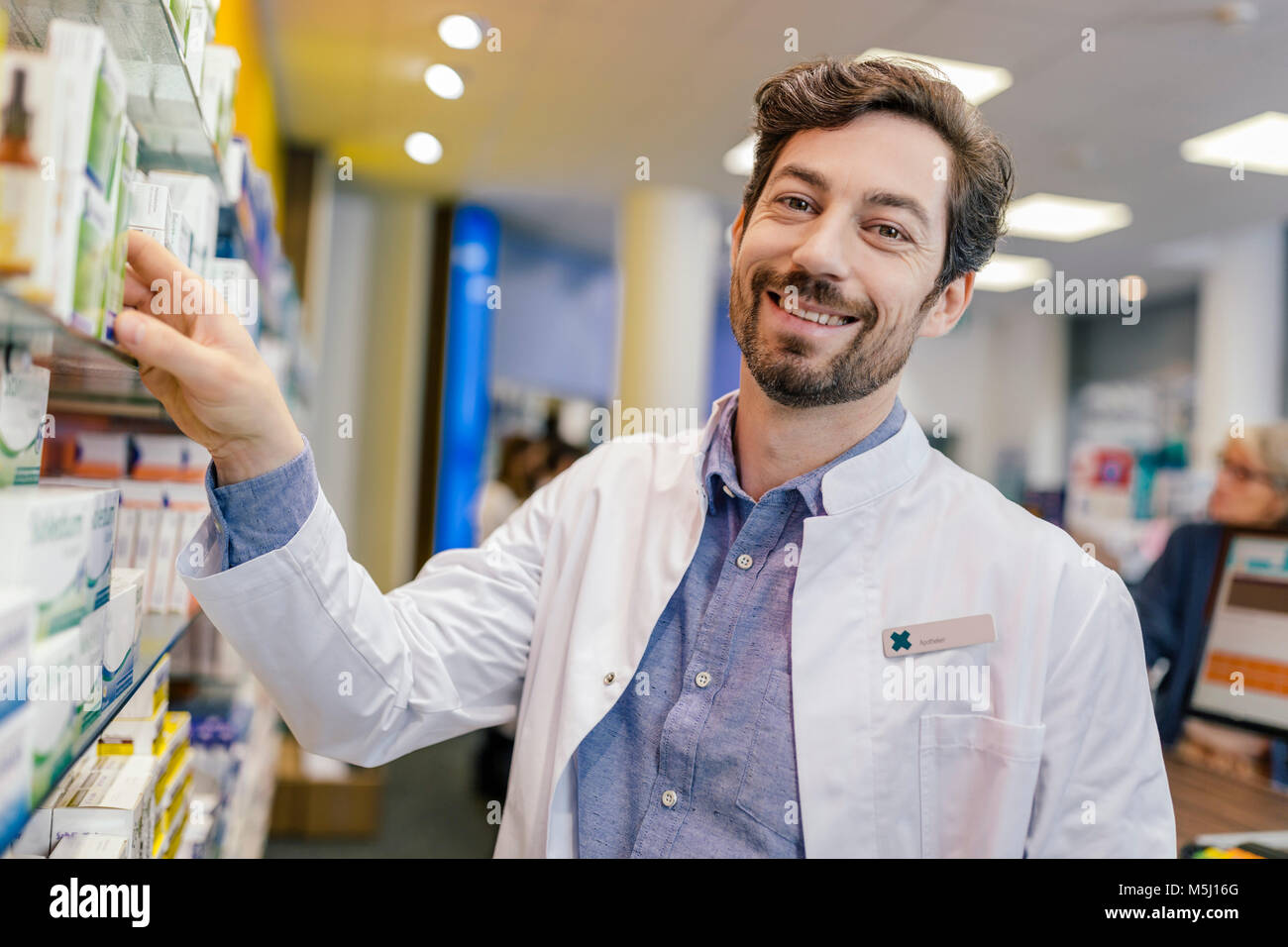 Portrait of smiling pharmacist with medicine at shelf in pharmacy Stock ...