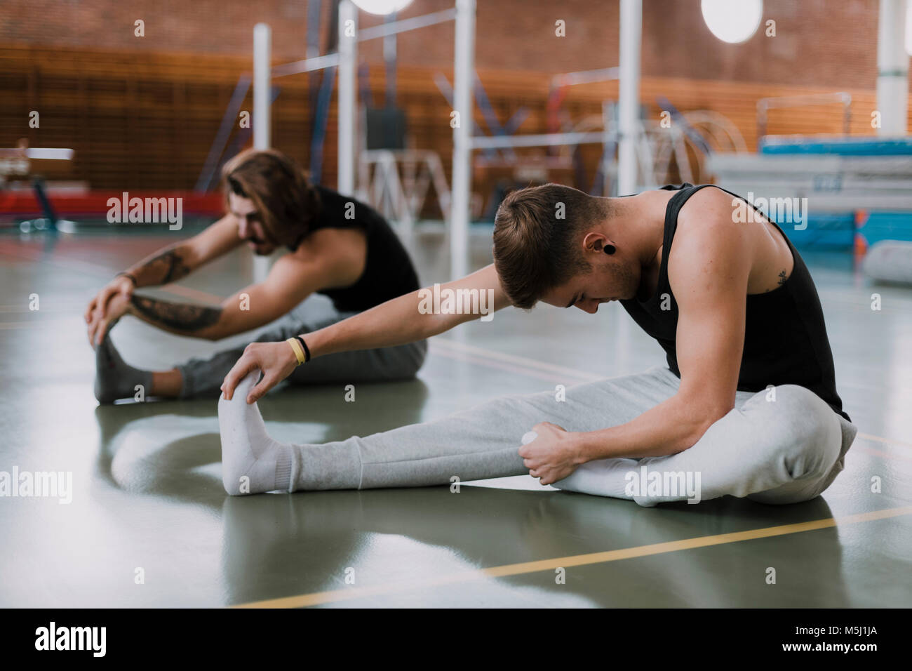 Two young men stretching in gym Stock Photo - Alamy