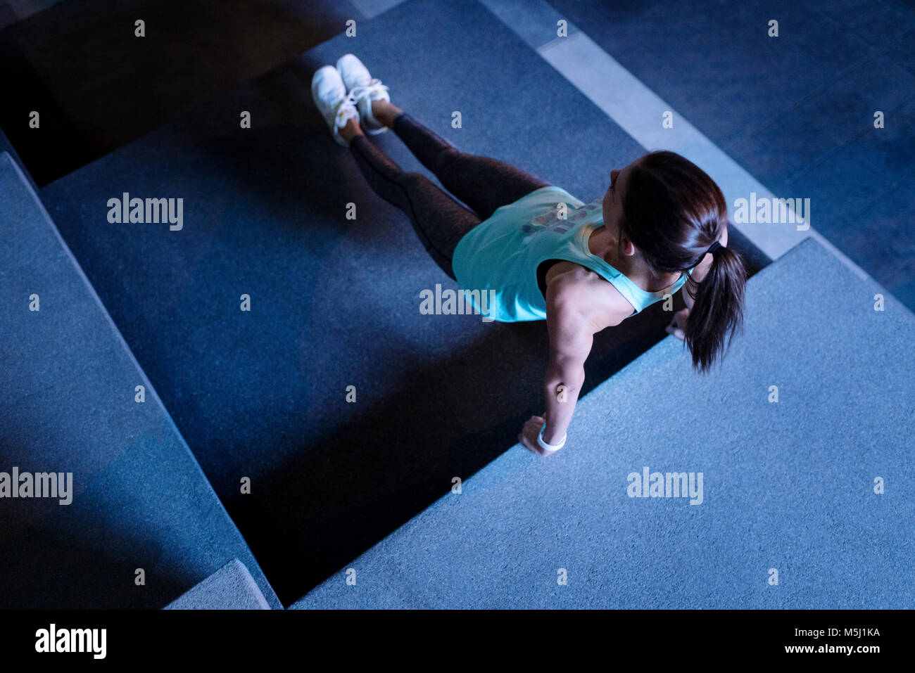 Young woman doing reverse pushups in modern urban setting at night ...