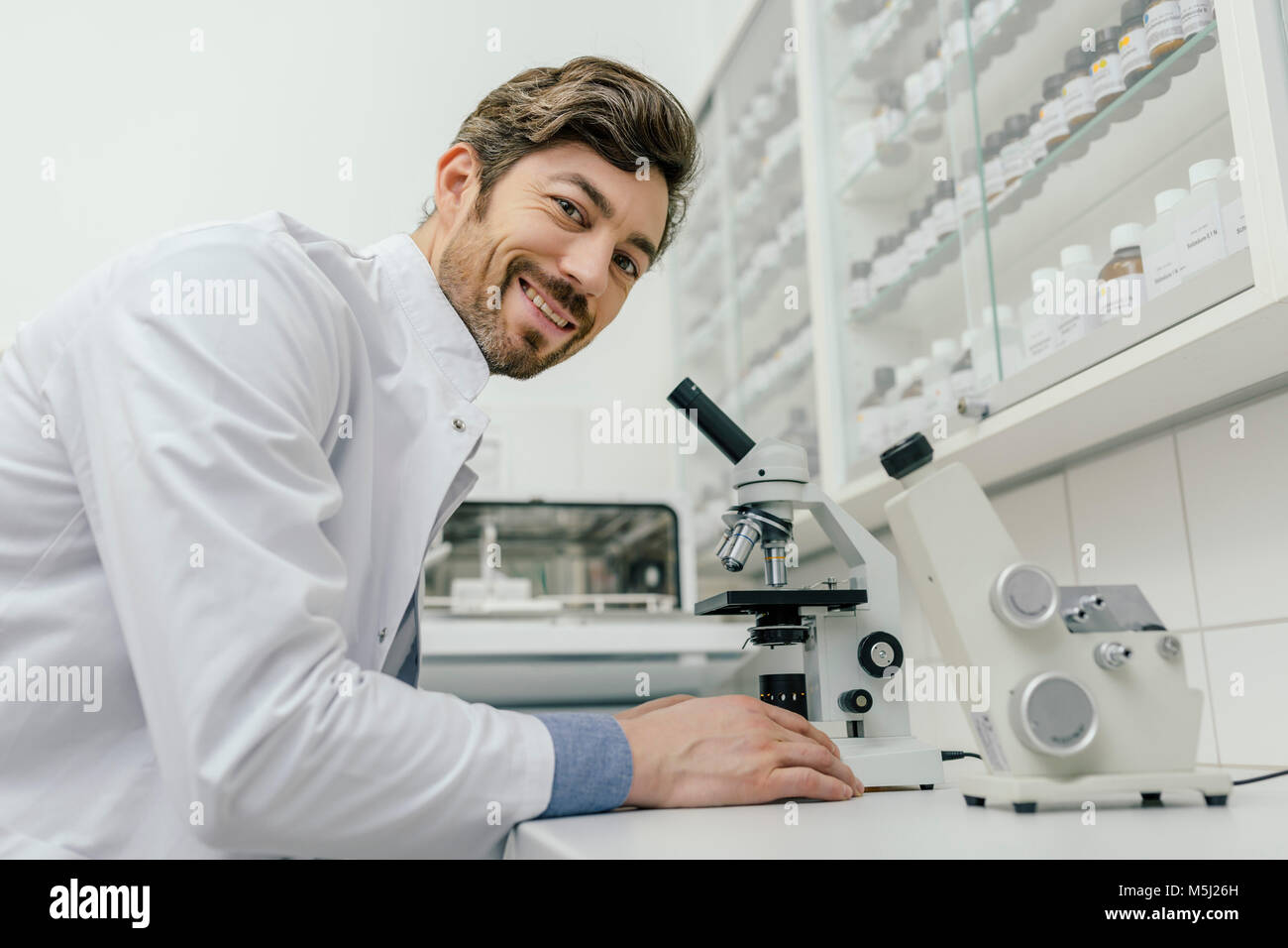 Portrait of smiling man using microscope in laboratory Stock Photo - Alamy