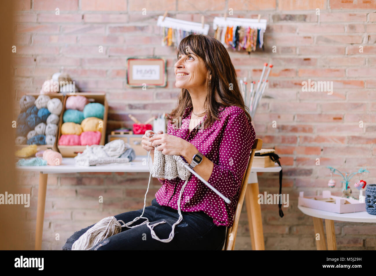 Smiling woman sitting on chair knitting Stock Photo - Alamy